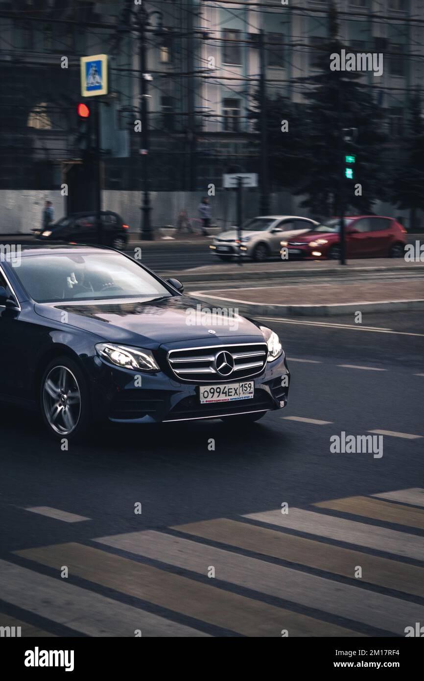 A vertical of a black Mercedes driving on the street shot in long ...