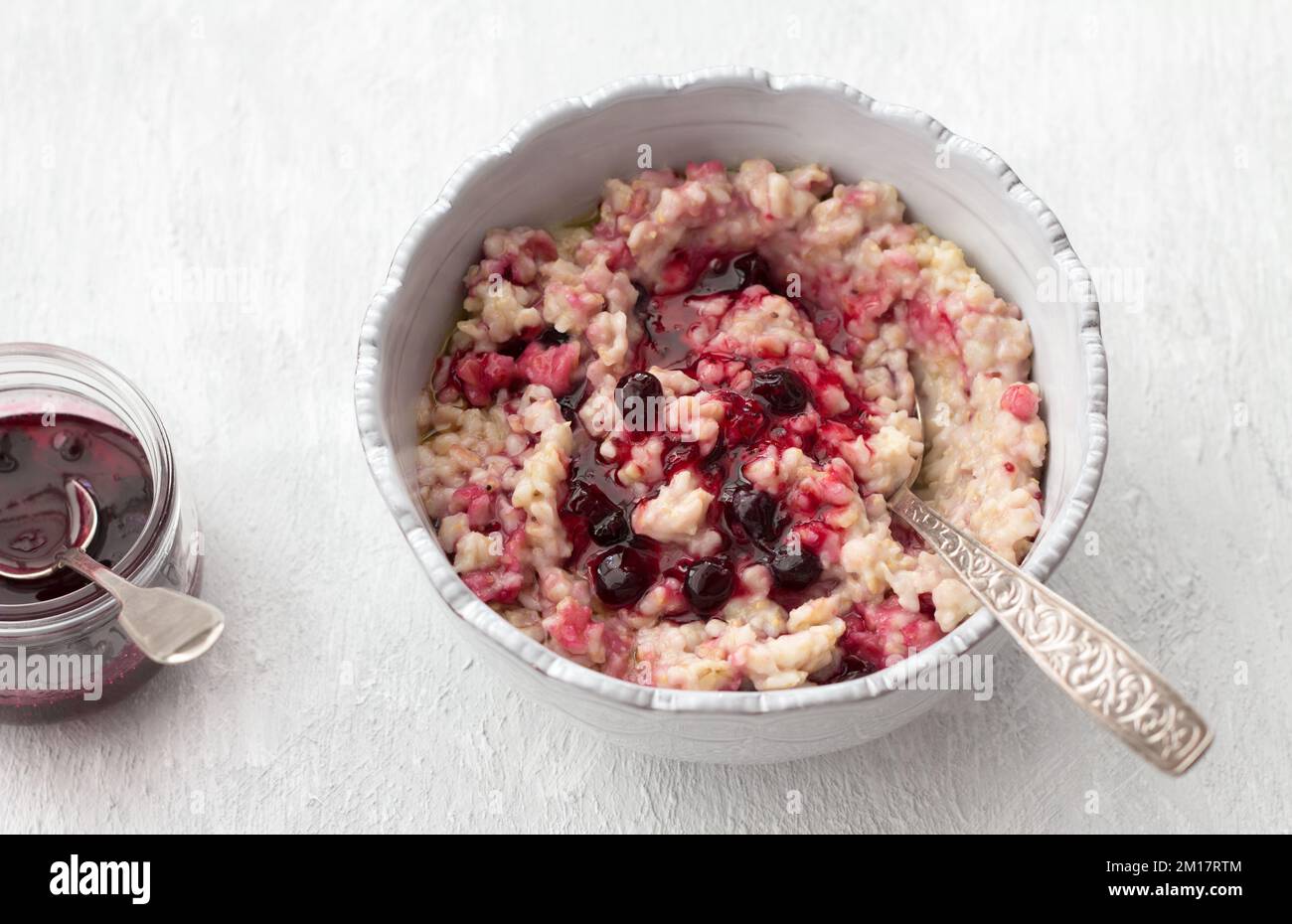 Delicious oatmeal porridge with butter and jam in a gray bowl on a ...