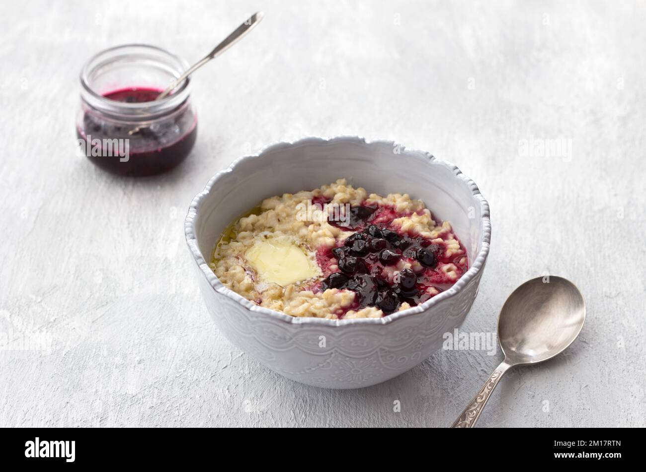Delicious oatmeal porridge with butter and jam in a gray bowl on a ...