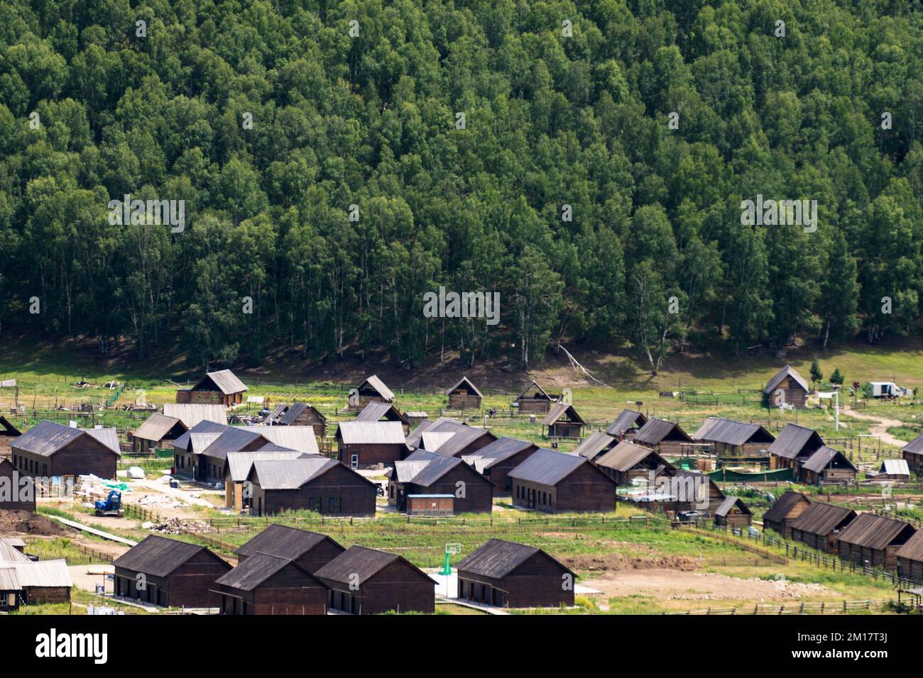 An aerial shot over small wooden houses in front of a dense green ...