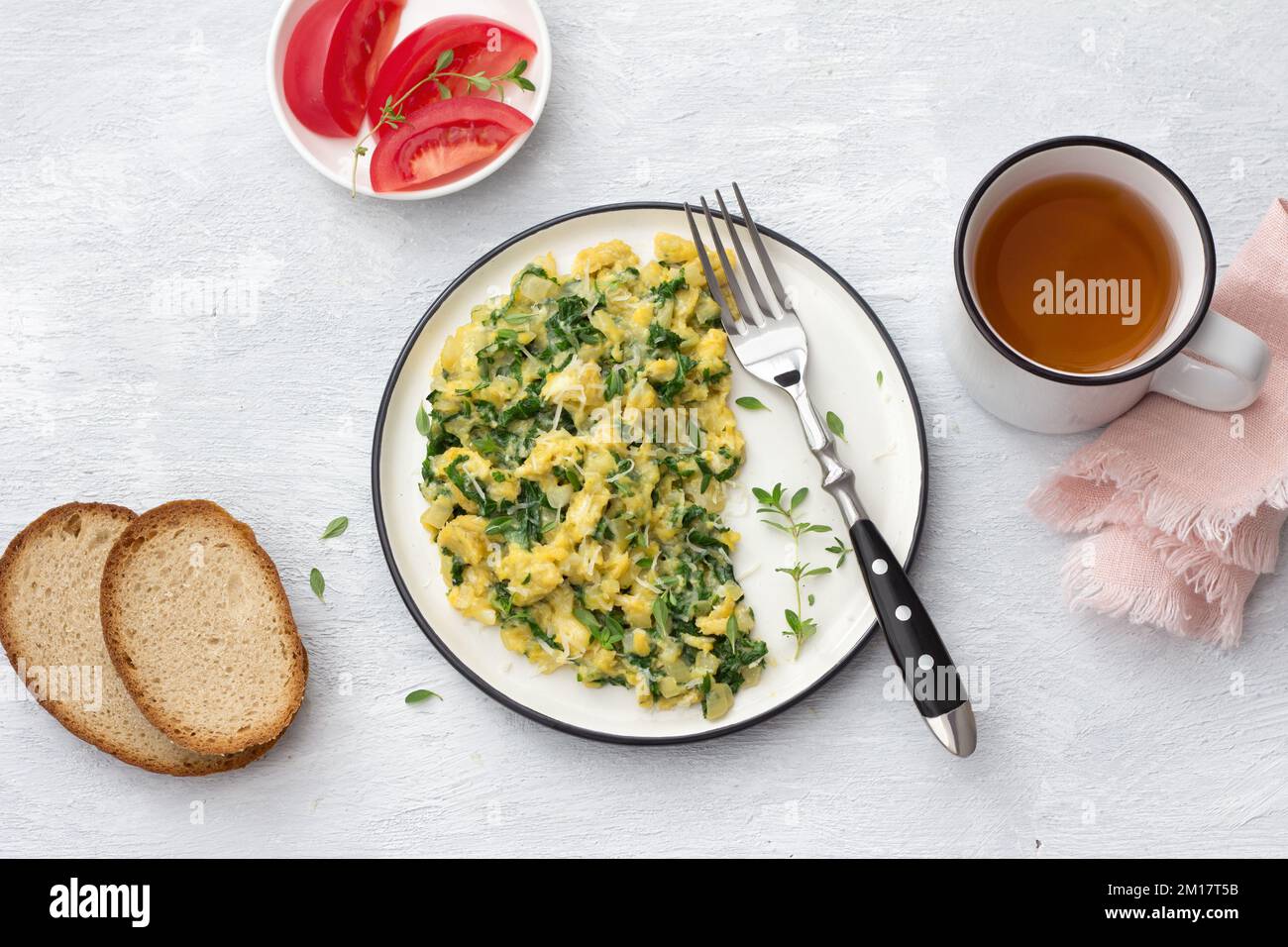Scramble eggs with kale and cheese on a light gray background, top view ...