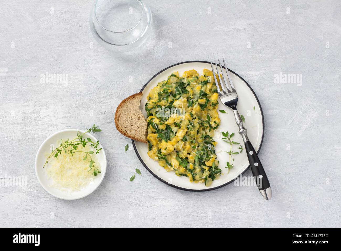 Scrumble eggs with kale and cheese on a light gray background, top view ...