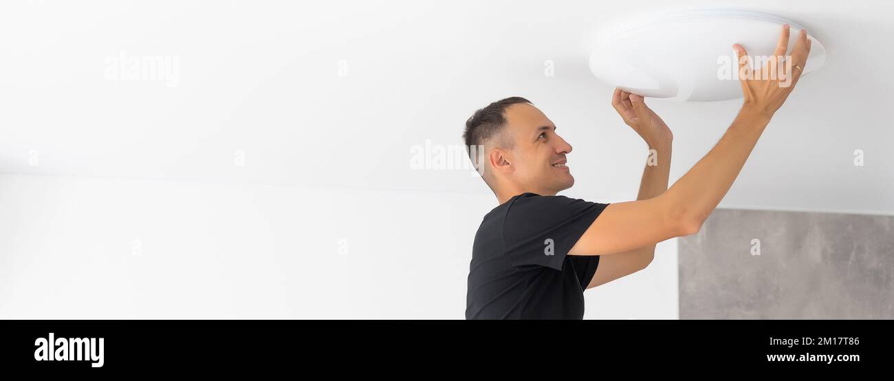 Worker repairing lamp on stretch ceiling indoors Stock Photo - Alamy