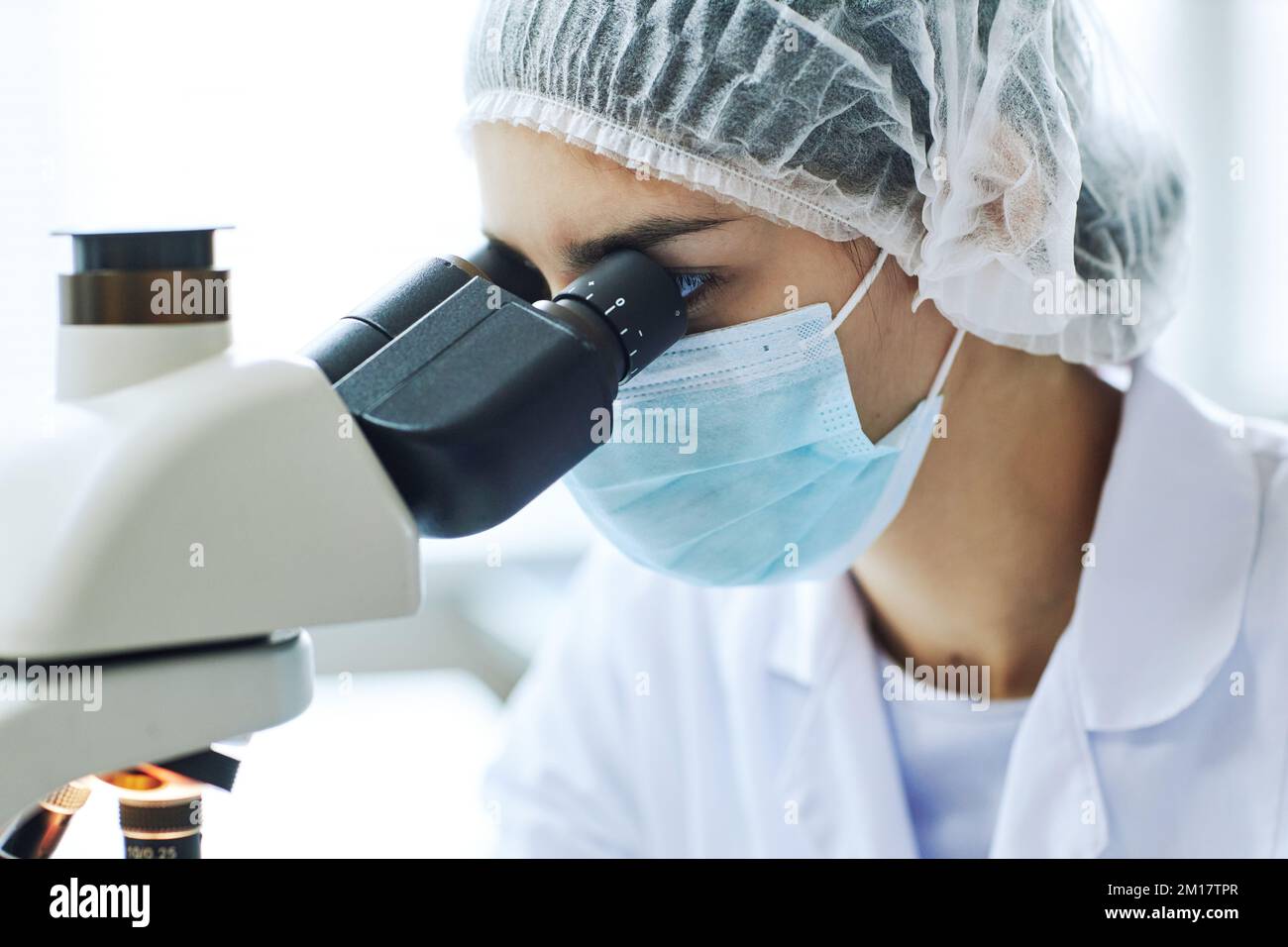 Close up portrait of female scientist looking in microscope while ...