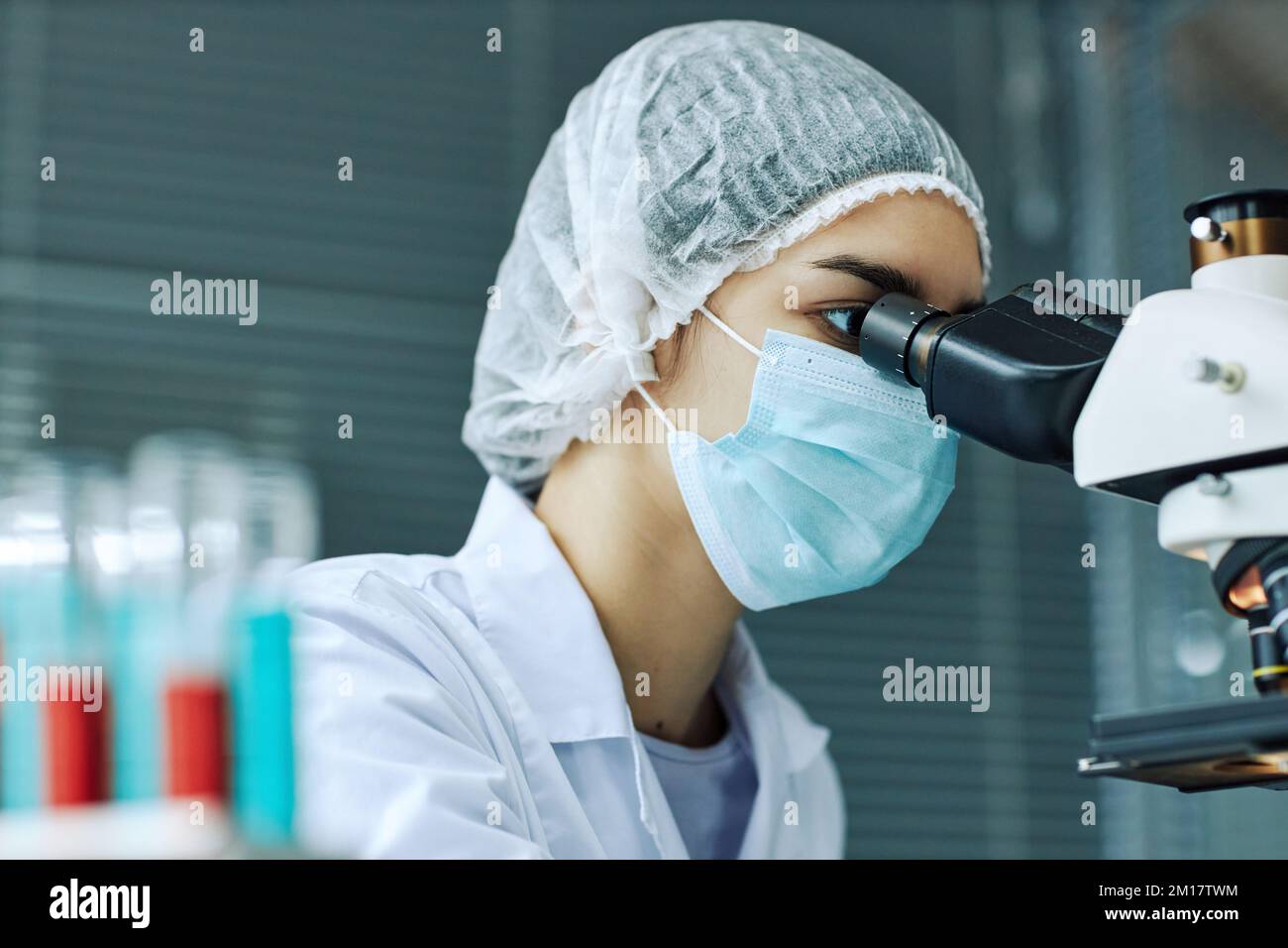 Side view portrait of young woman looking in microscope while working ...