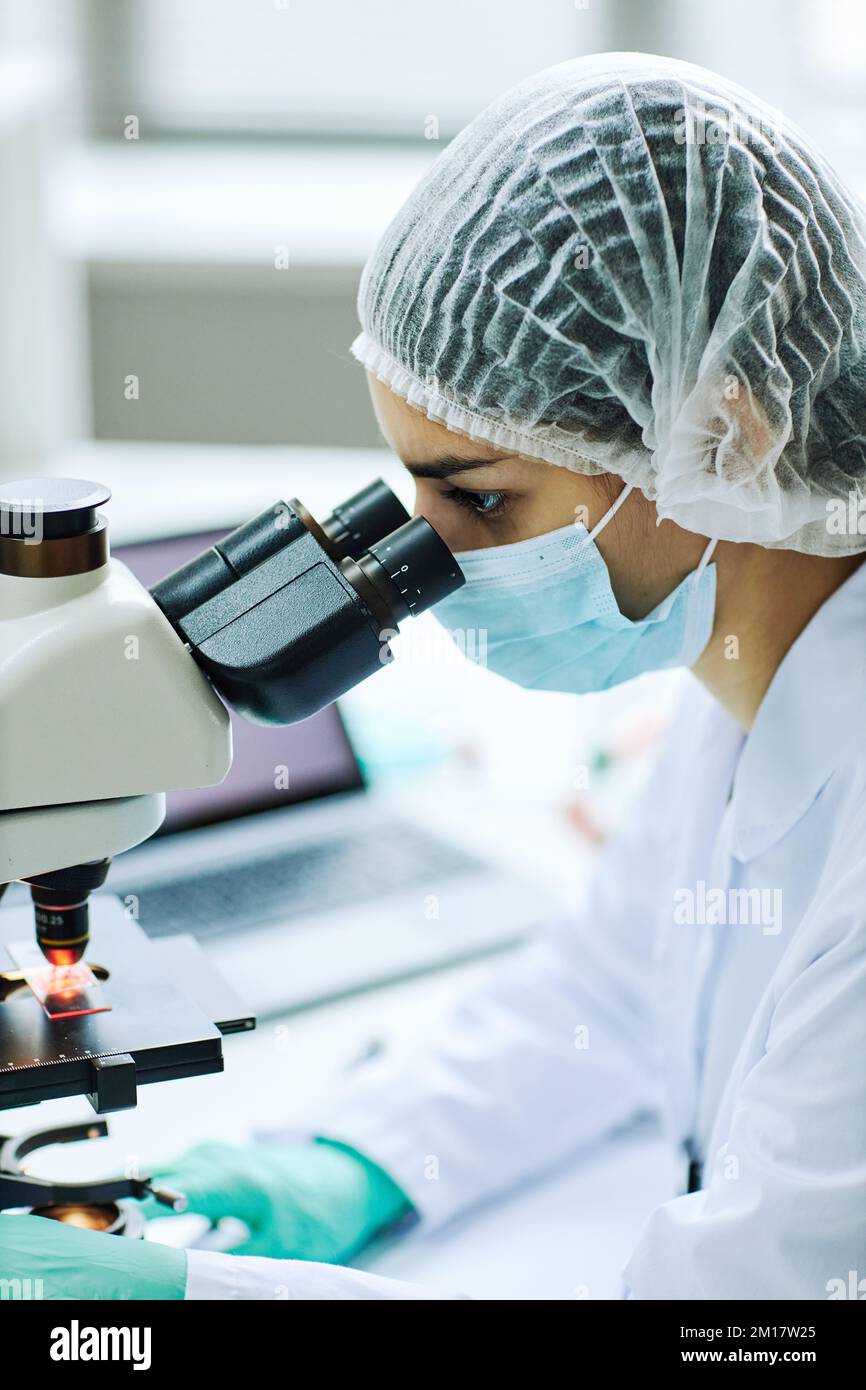 Vertical side view portrait of young female technician looking in ...