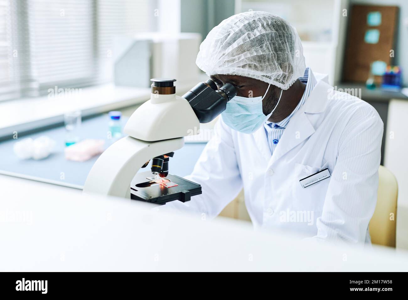 High angle view at black male scientist looking in microscope while ...