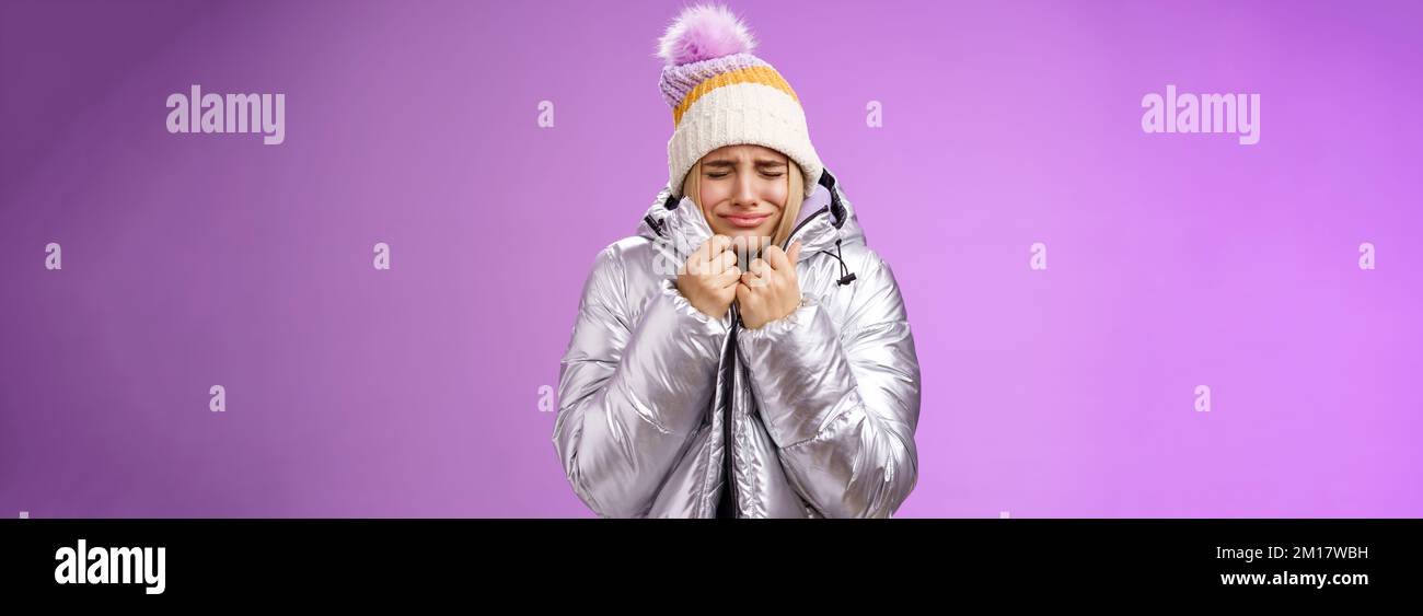 Unhappy sobbing whining cute blond girl pull jacket tight body close ...
