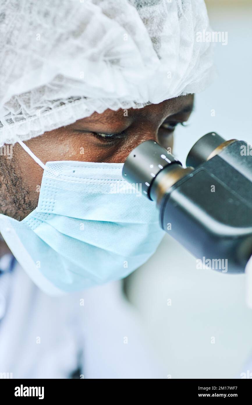 Vertical close up of male African American scientist looking in ...