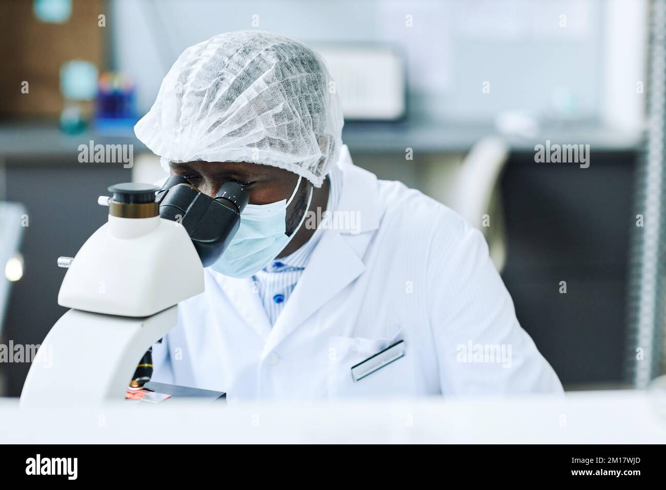 Portrait of black man looking in microscope and working on medical research in lab Stock Photo ...