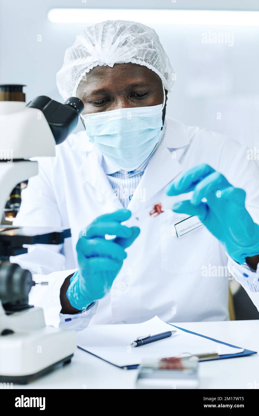 Vertical portrait of African American scientist doing blood tests in ...