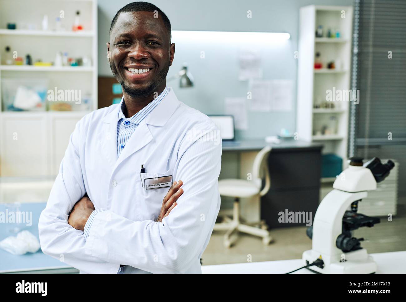 Waist up portrait of black young man wearing lab coat posing in clinic ...