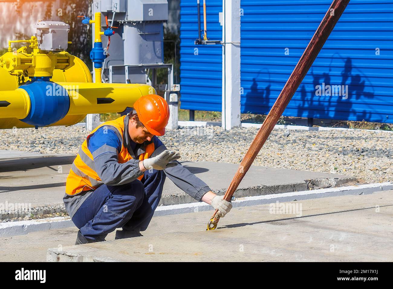 Slinger lays concrete slab on construction site on summer day. Worker ...