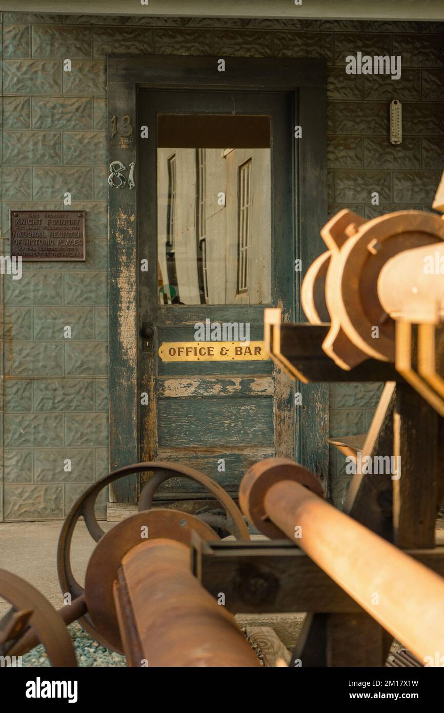 A vertical shot of a green wooden door with "office and bar" sign ...