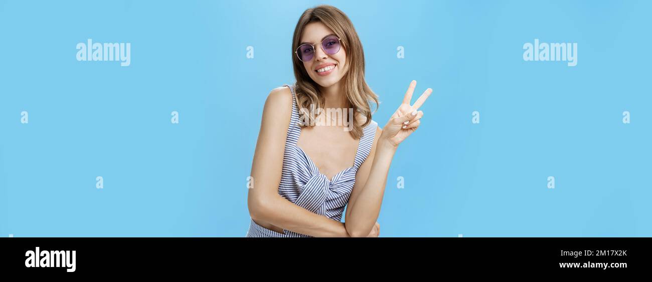 Charming friendly and outgoing young lady showing peace or victory ...