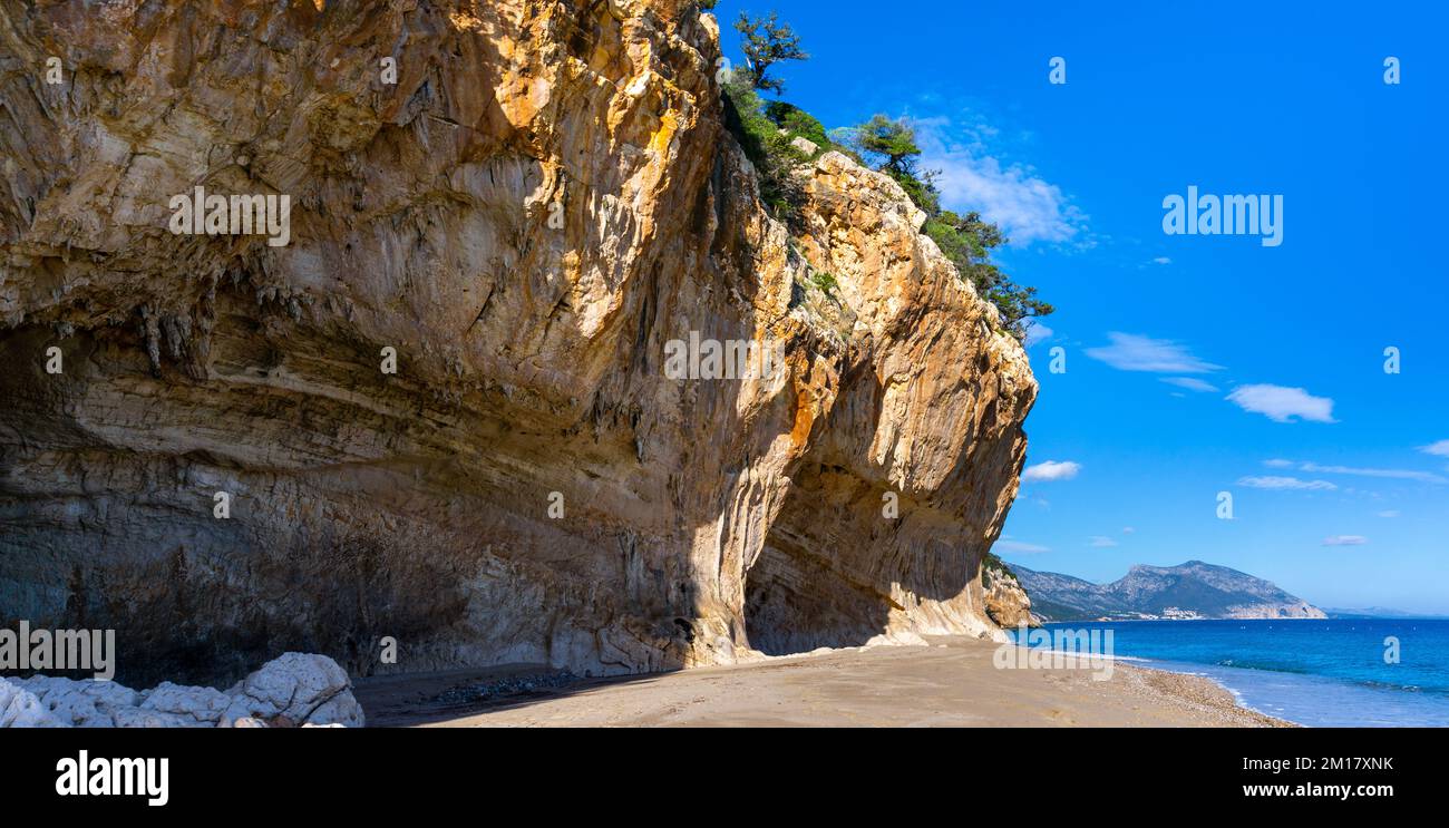The overhanging cliffs and sandy beach at Cala Luna on the east coast ...