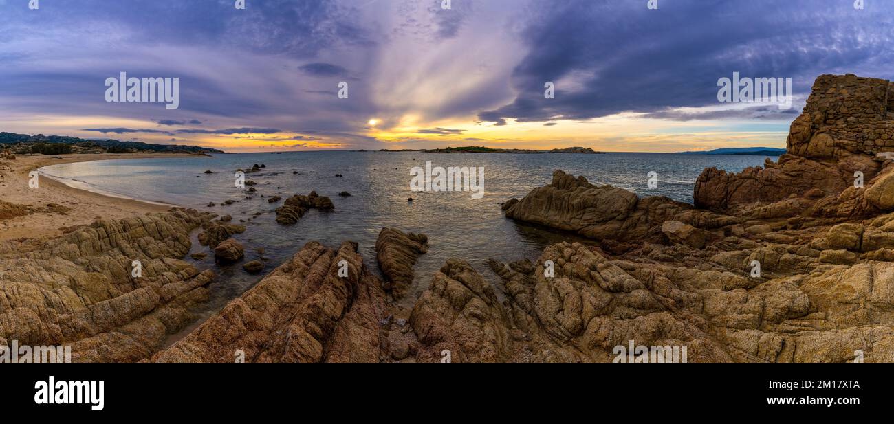 A panorama view of a golden sand beach at sunset with calm ocean water ...