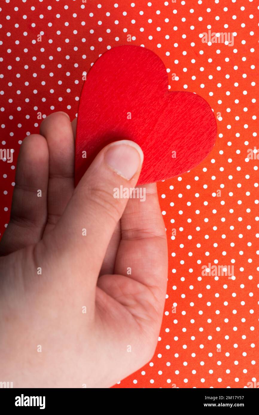 Red color heart shaped object in hand on dotted paper Stock Photo - Alamy