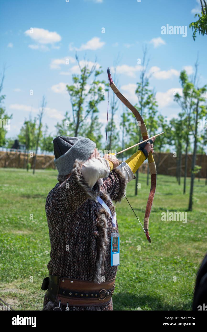 Archer with bow in traditional clothes shooting an arrow Stock Photo ...