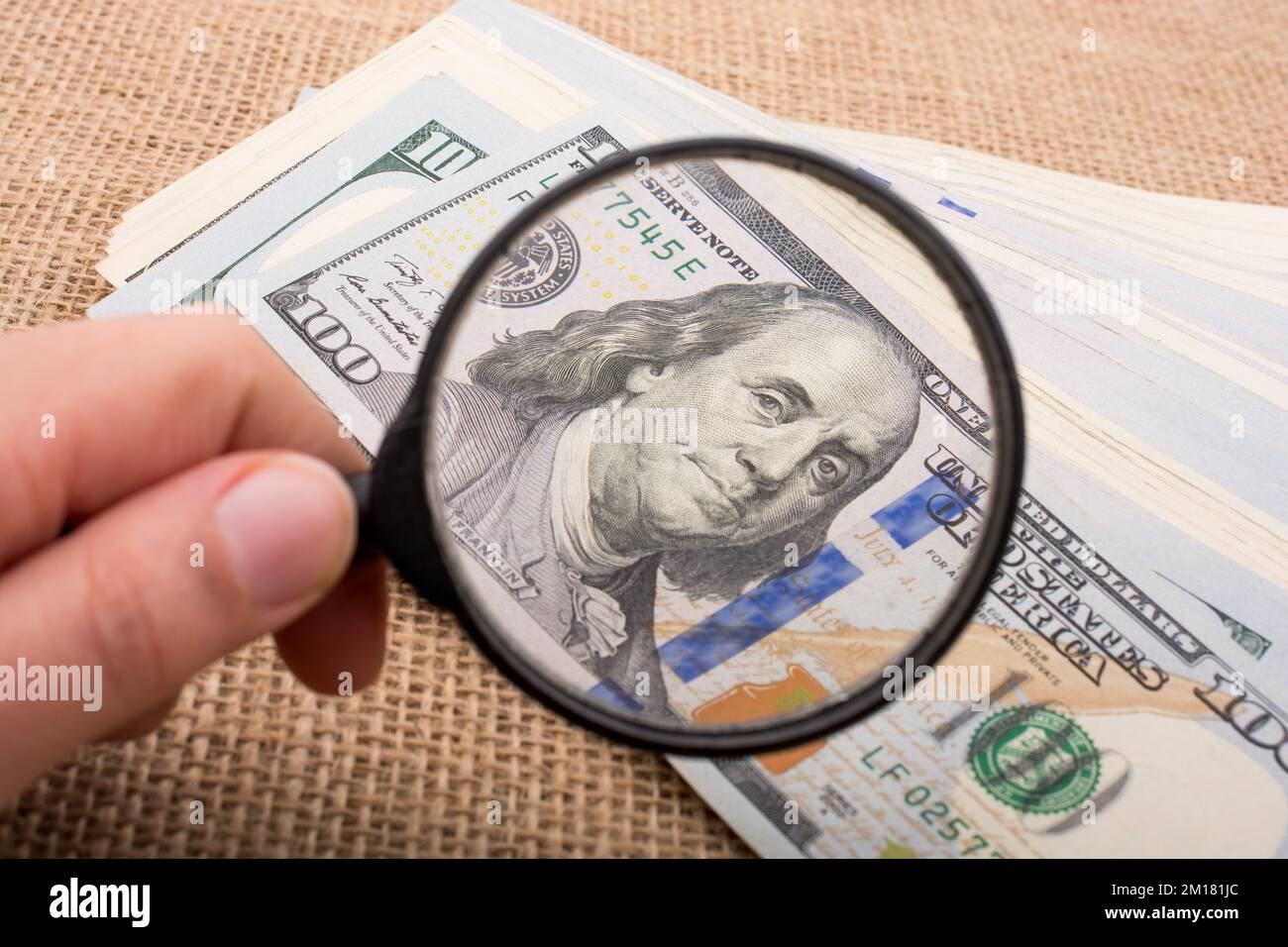 Magnifying glass is held over the banknote bundle of US dollar Stock ...