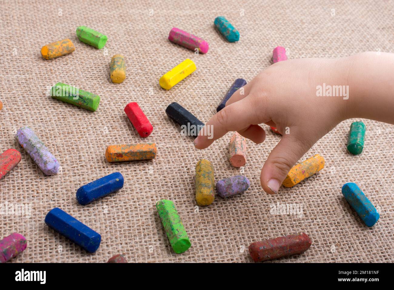 Used color crayons and a toddlers hand pointing Stock Photo - Alamy