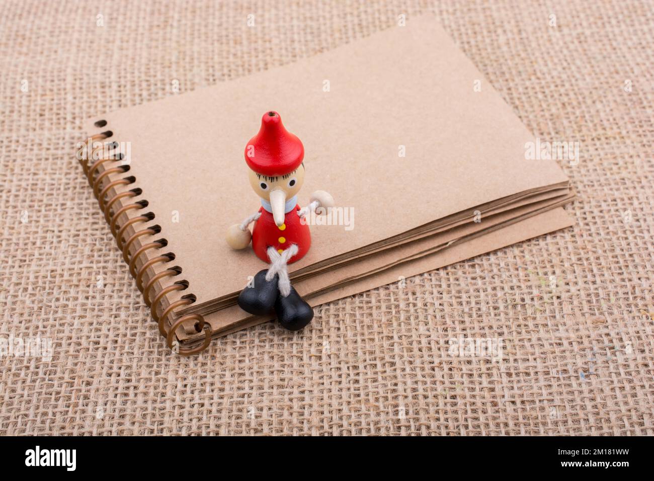 Pinocchio sitting on notebook on a canvas background Stock Photo - Alamy