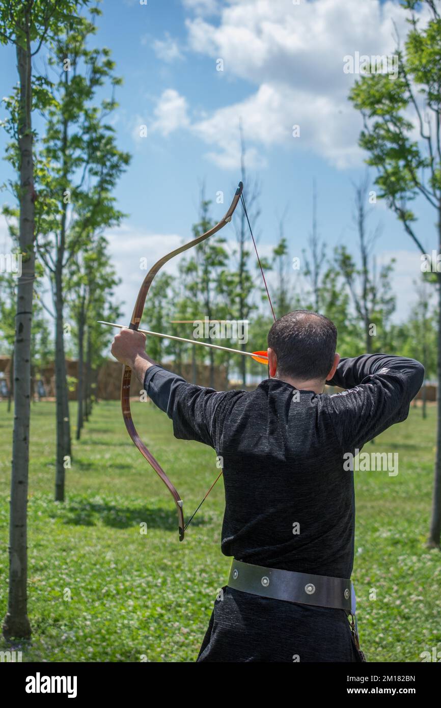 Archer with bow in traditional clothes shooting an arrow Stock Photo ...