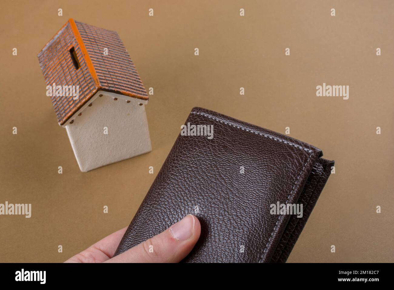 Little model house beside a wallet in hand Stock Photo - Alamy