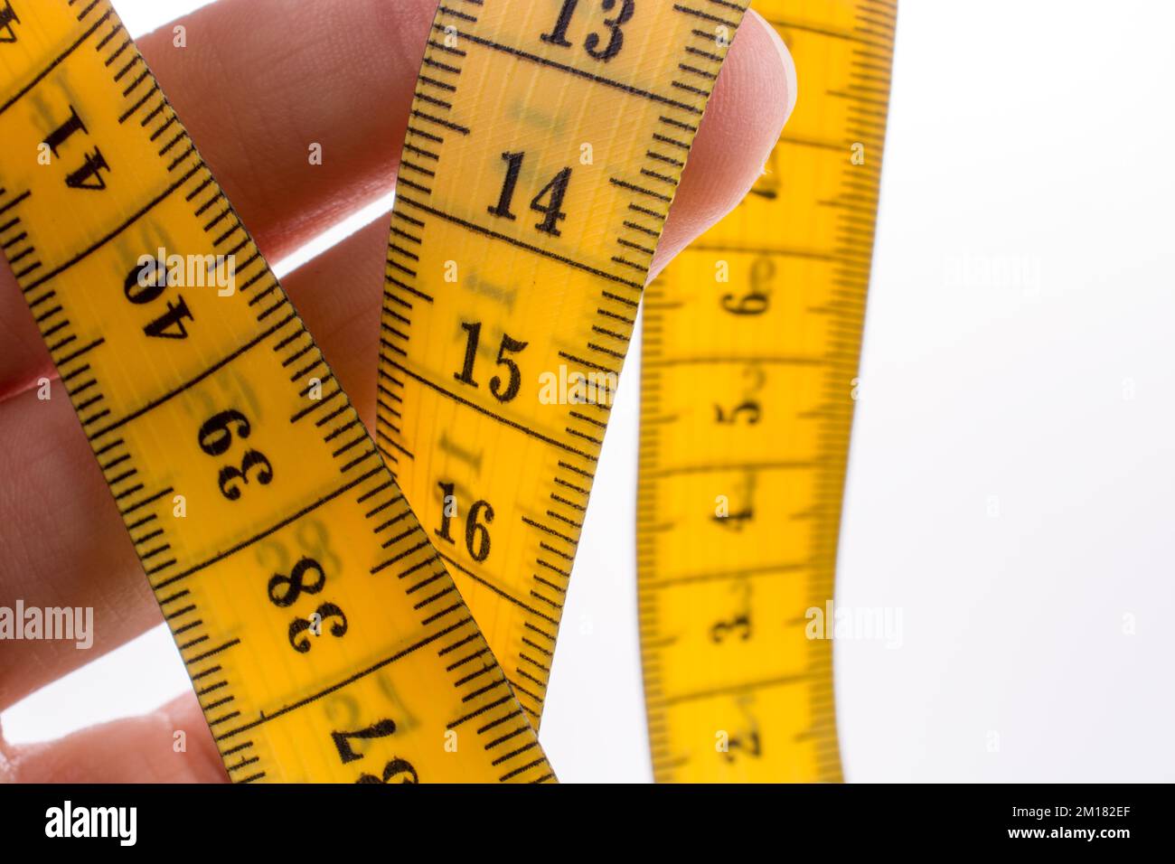 Hand holding a yellow measuring tape Stock Photo - Alamy