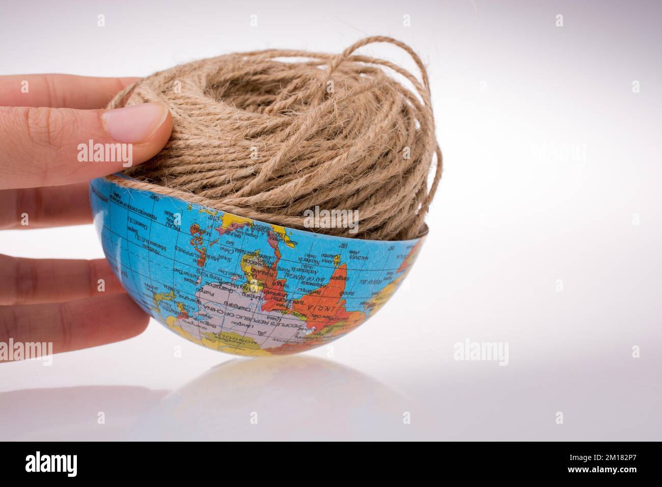 Spool of thread placed in a little colorful model globe Stock Photo - Alamy