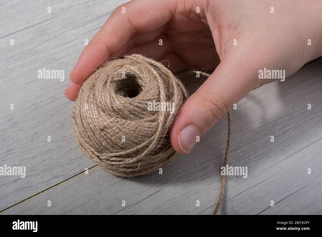 Spool of brown string in hand on white background Stock Photo - Alamy