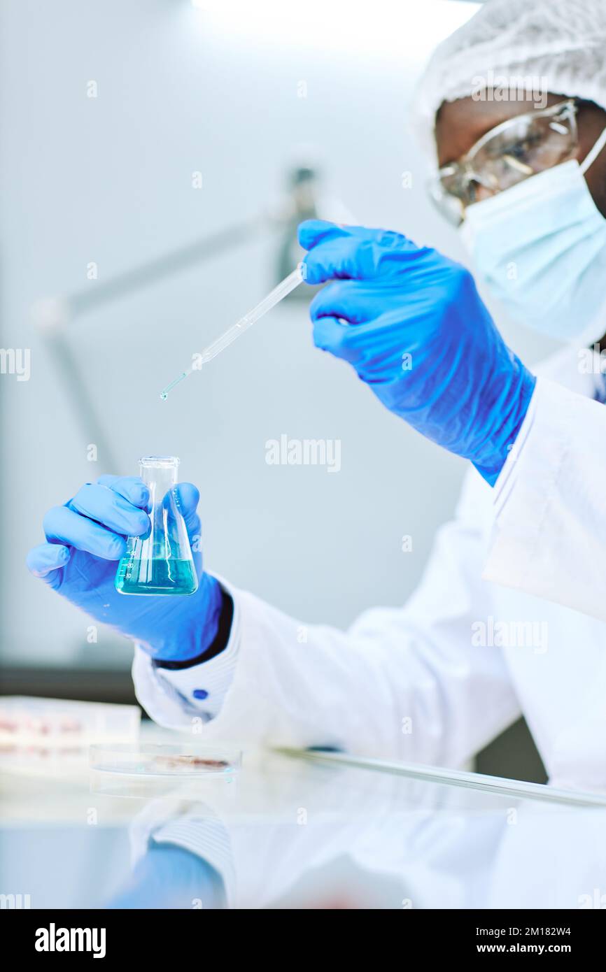 Vertical close up of African American lab technician taking liquid ...