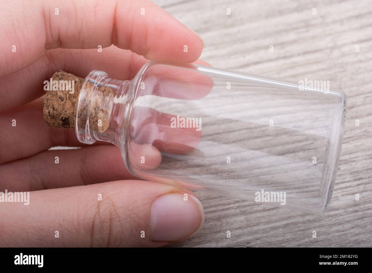 Little empty glass bottle in hand on a white background Stock Photo - Alamy