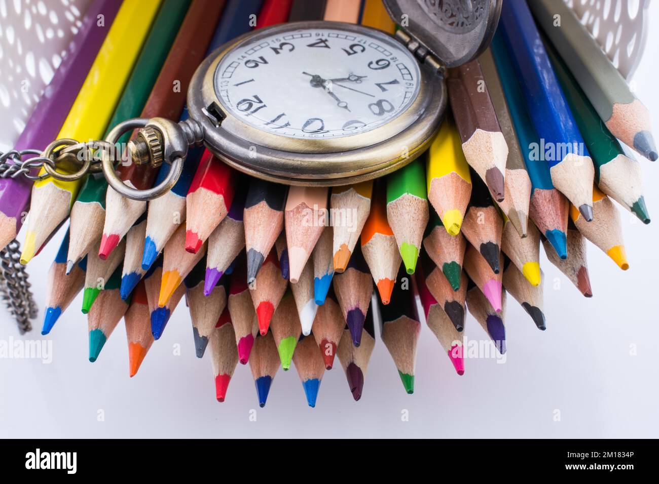 Retro style classic pocket watch and color pencils on white background ...