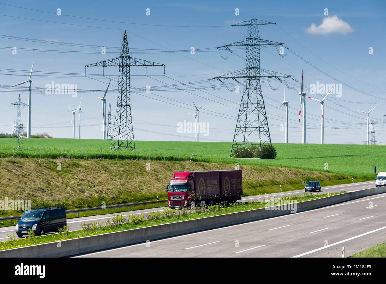 Agricultural landscape with overhead powerlines, cars on a highway and ...