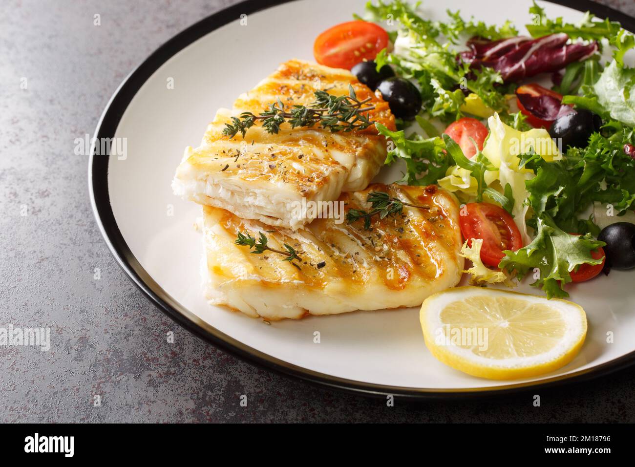 Diet food grilled fish cod with fresh salad of tomatoes, olives ...