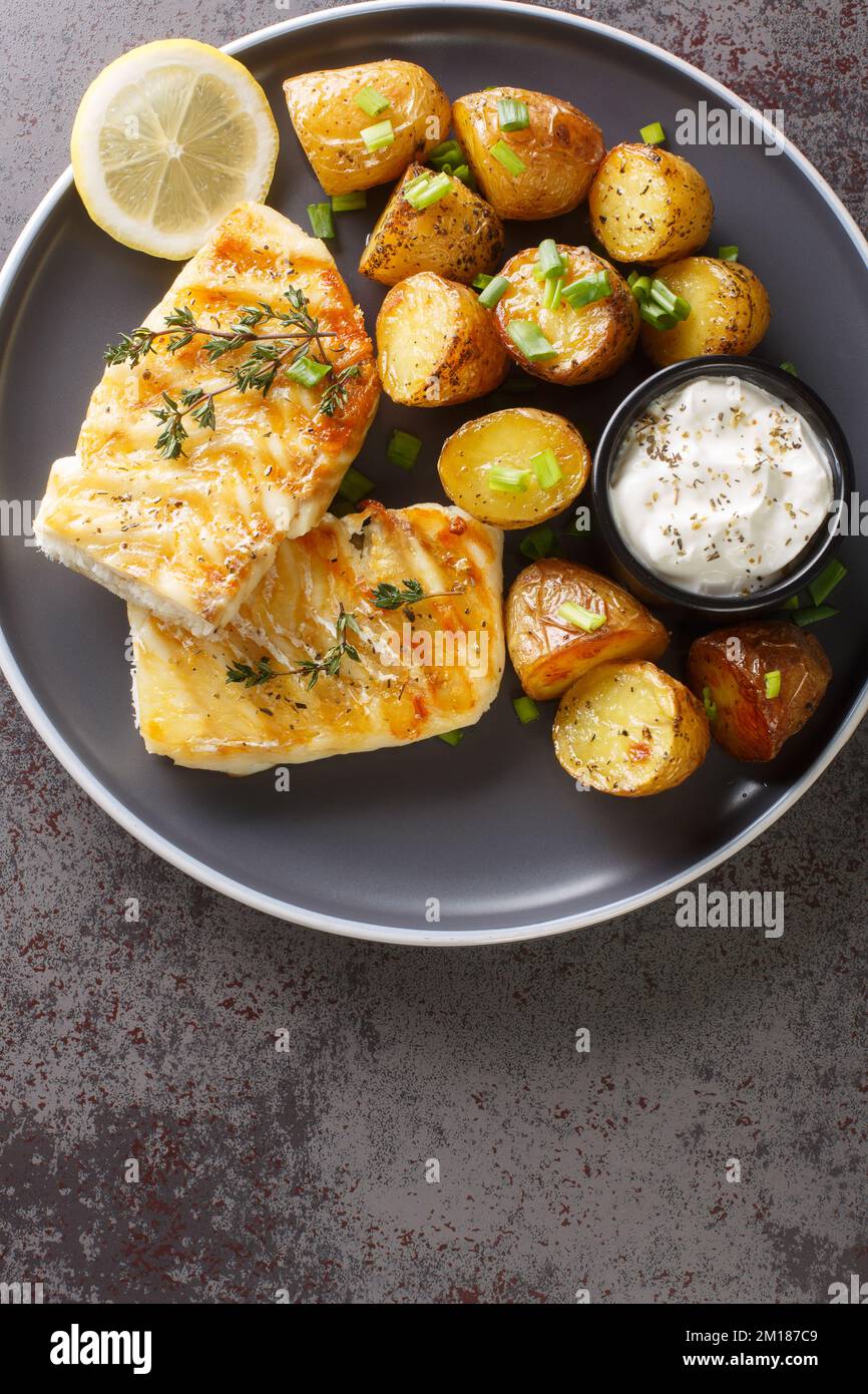 Healthy dinner of grilled white fish with baked potatoes close-up in a ...