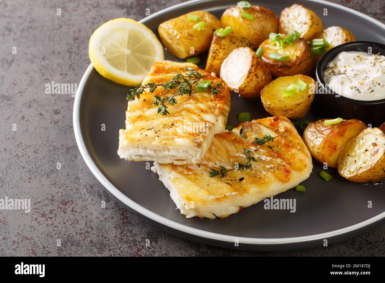 Close-up dish of grilled codfish with baked jacket potatoes, creamy ...