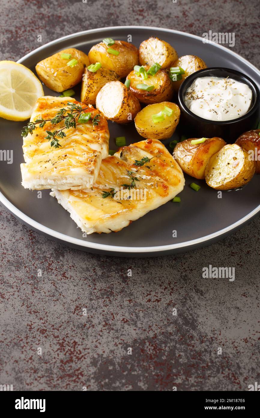 grilled cod fish with baked jacket potatoes, cream sauce and lemon ...