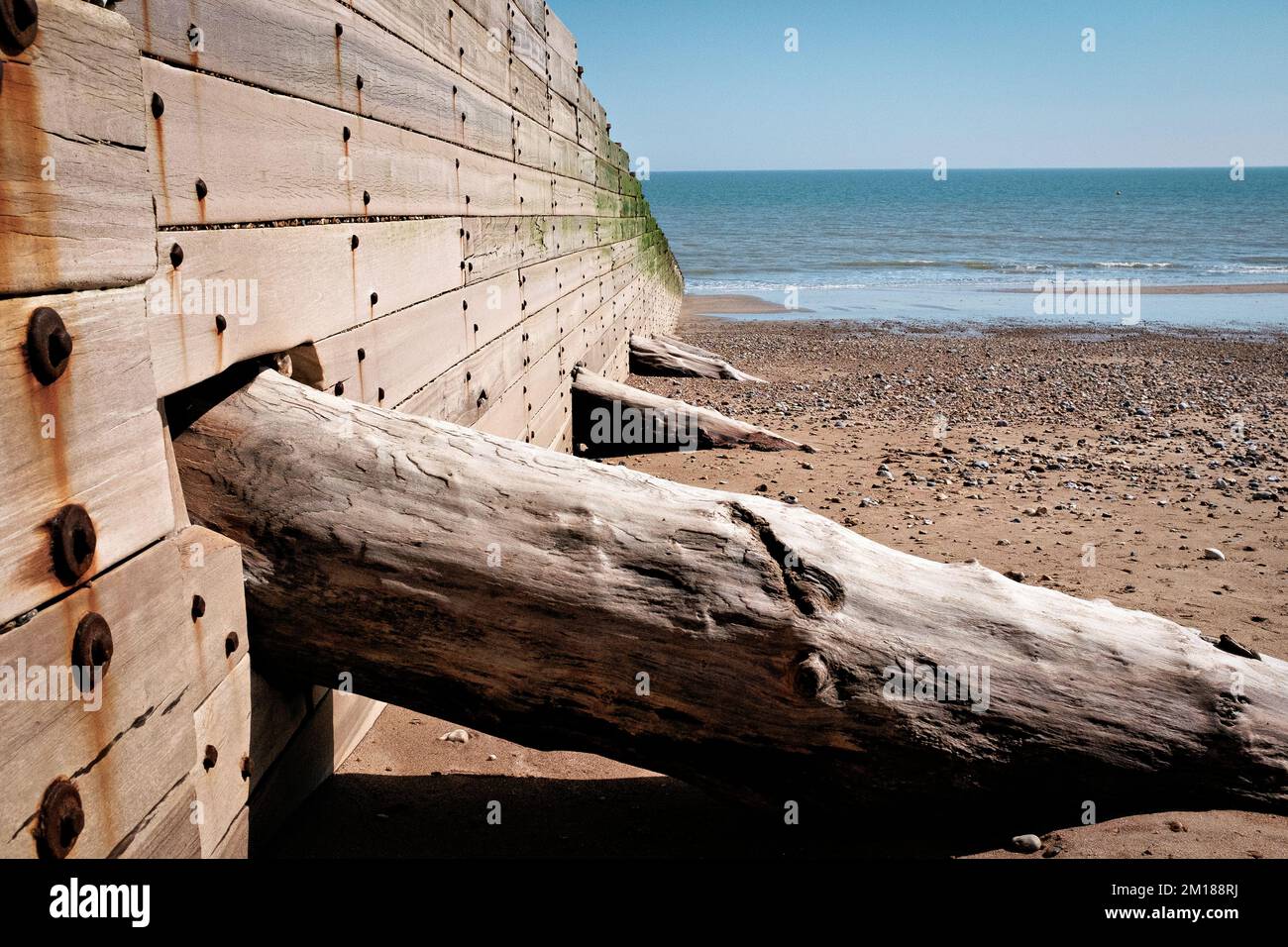 A beach groyne and supports leading across a beach with sand and ...