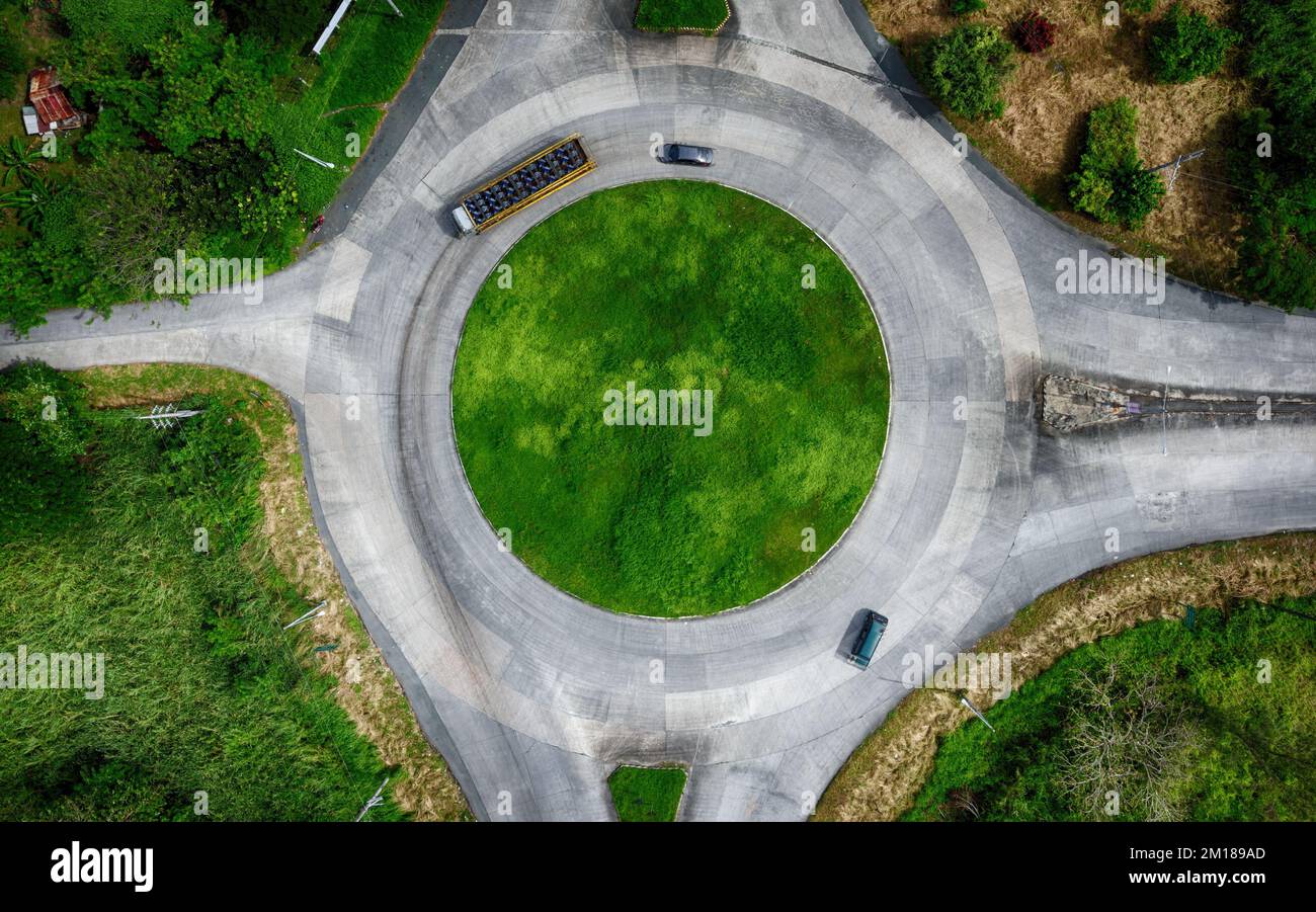 An aerial view of scattered vehicles on a roundabout surrounded by lush green areas Stock Photo ...