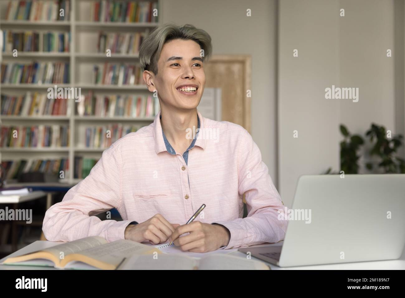 Cheerful smart Asian student guy working on article Stock Photo - Alamy