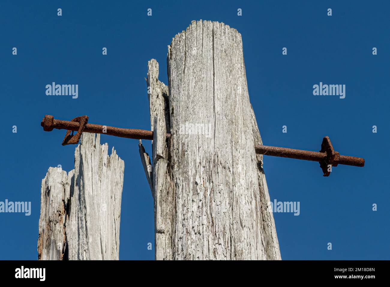 A low angle shot of rusty metal pole into old weathered wooden fence ...