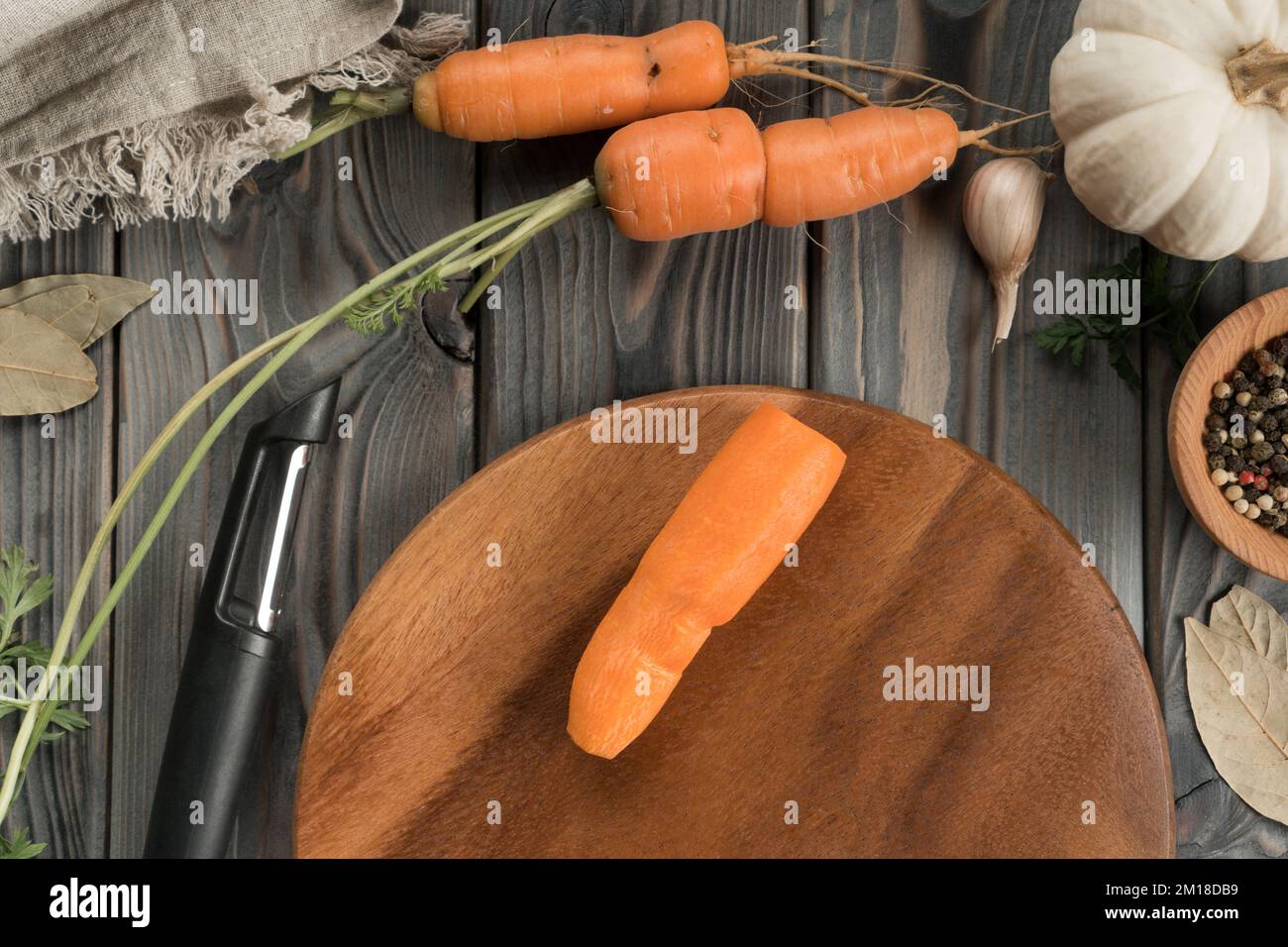 Peeling ripe orange carrot with vegetable peeler. Flat lay view. Fresh ...