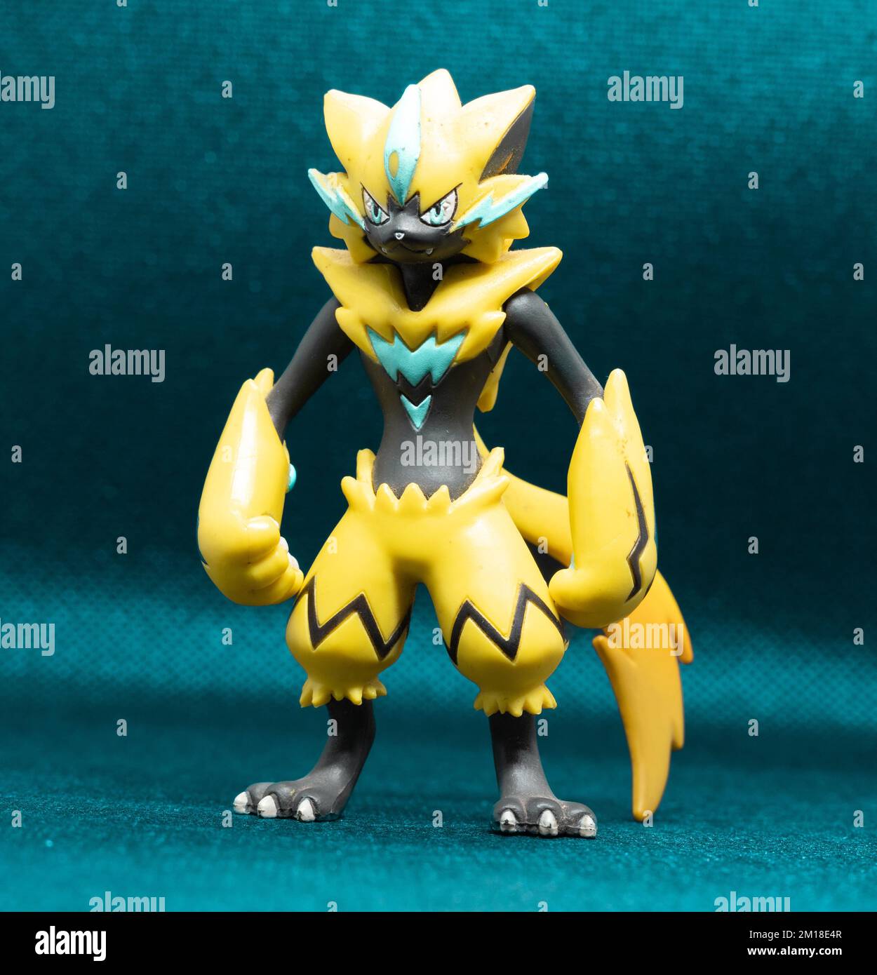 A yellow and black Zeroara Pokemon Action Figure on turquoise ...