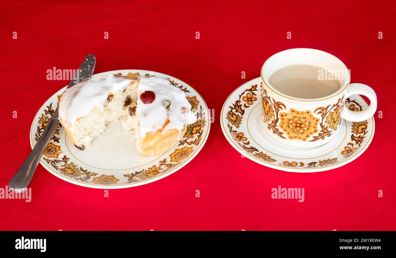 A Belgian bun and a cup of tea against a red background Stock Photo - Alamy