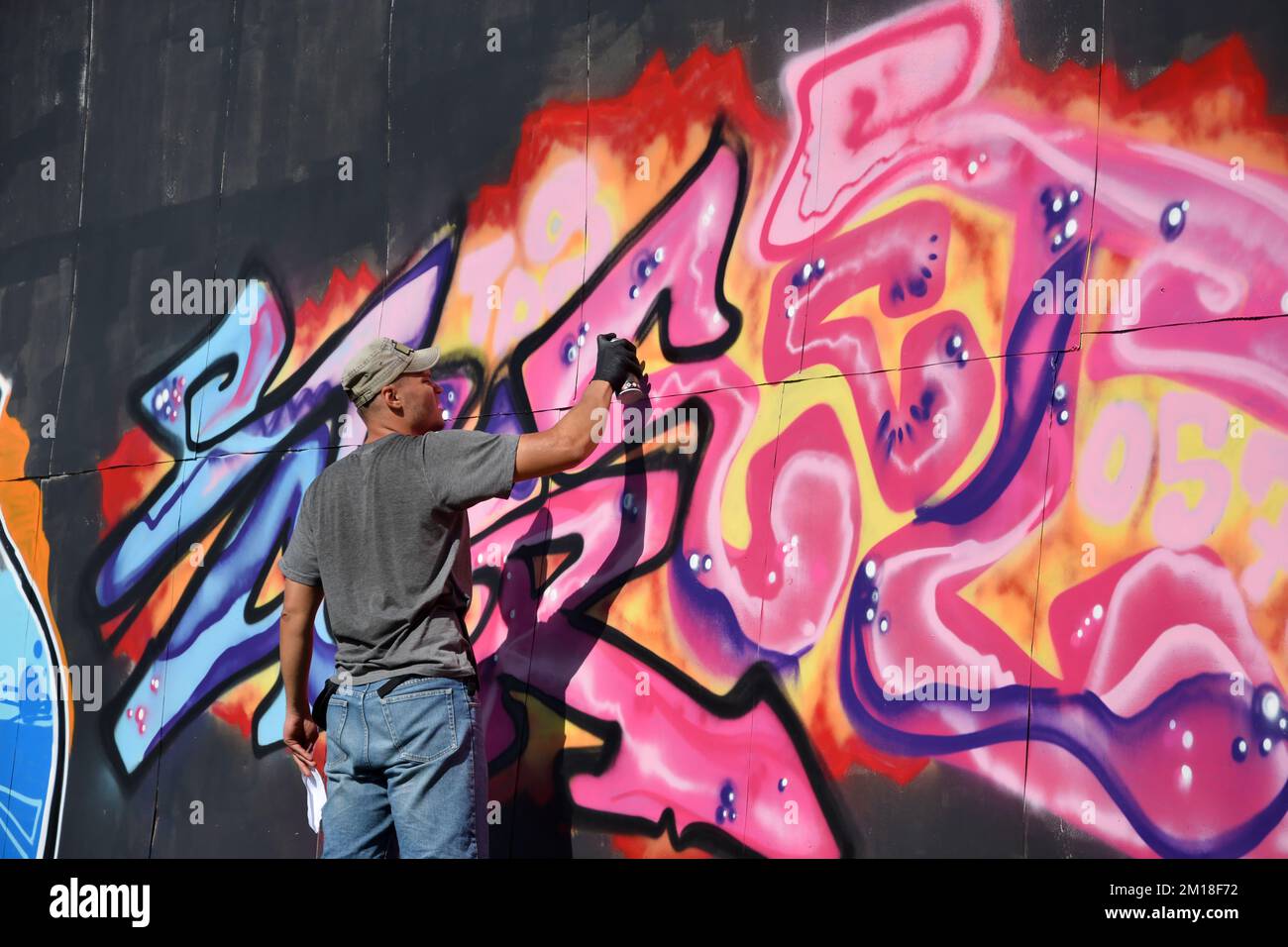 Young caucasian male graffiti artist drawing big street art painting in ...