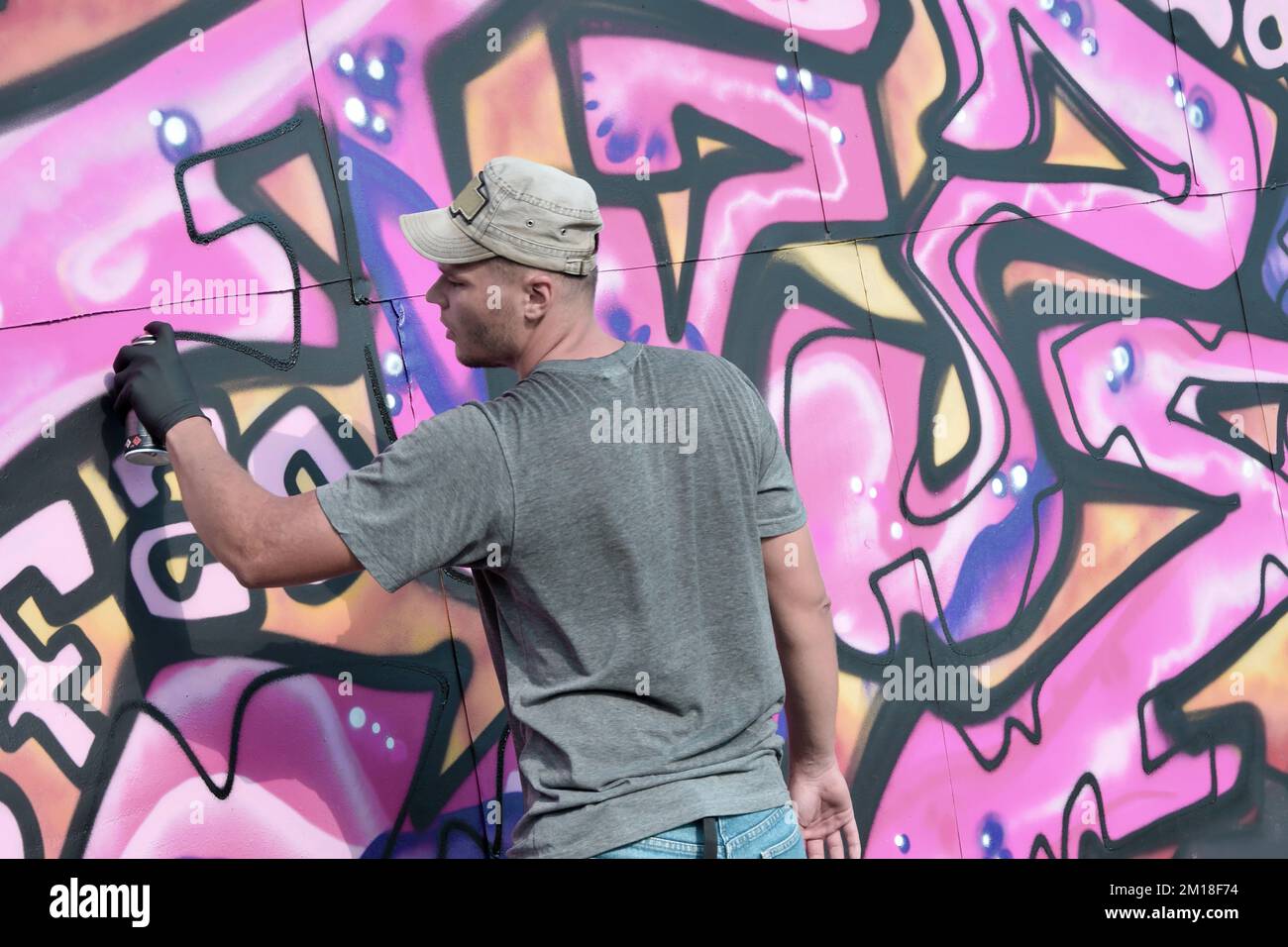 Young caucasian male graffiti artist drawing big street art painting in ...