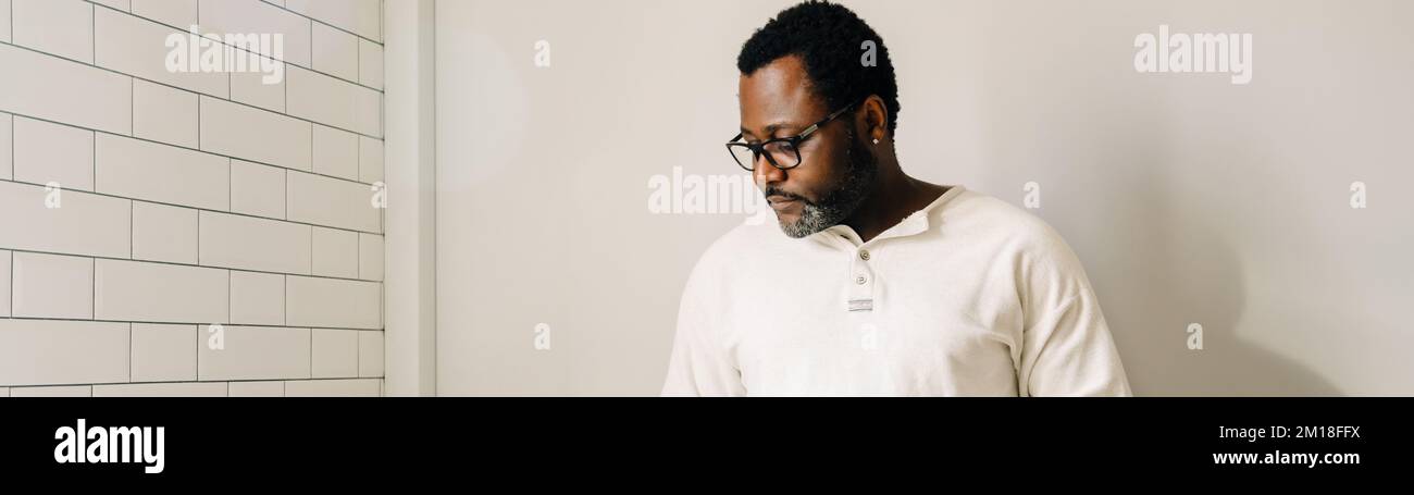 Mature african american man wearing eyeglasses standing over white wall ...