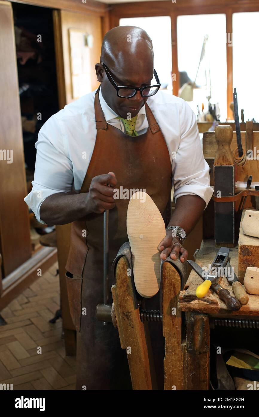 Portrait of a shoemaker at Lobb Shoes, St James, London holding a ...